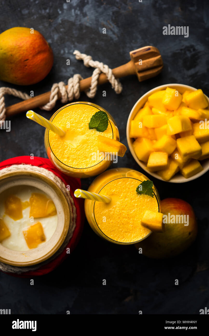 Mango Lassi or smoothie in big glass or small bottles with curd, cut ...