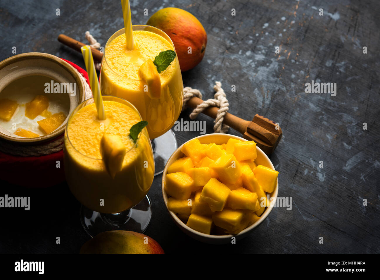 Mango Lassi or smoothie in big glass or small bottles with curd, cut ...