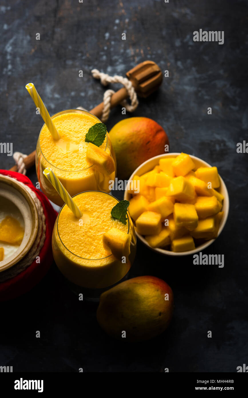 Mango Lassi or smoothie in big glass or small bottles with curd, cut ...