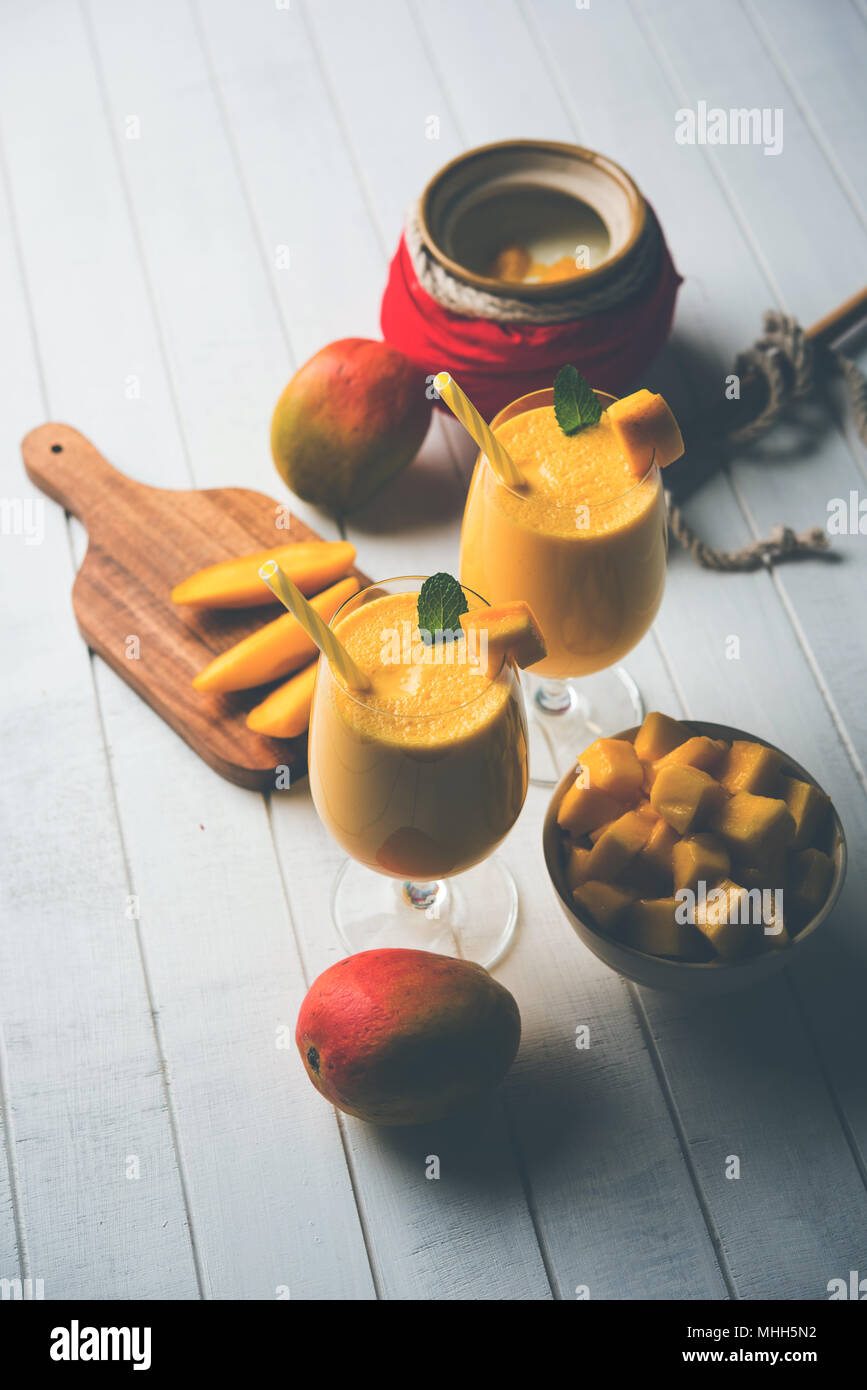 Mango Lassi or smoothie in big glass or small bottles with curd, cut ...