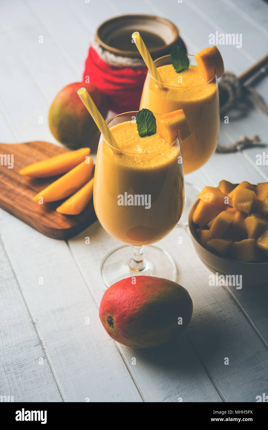 Mango Lassi or smoothie in big glass or small bottles with curd, cut ...