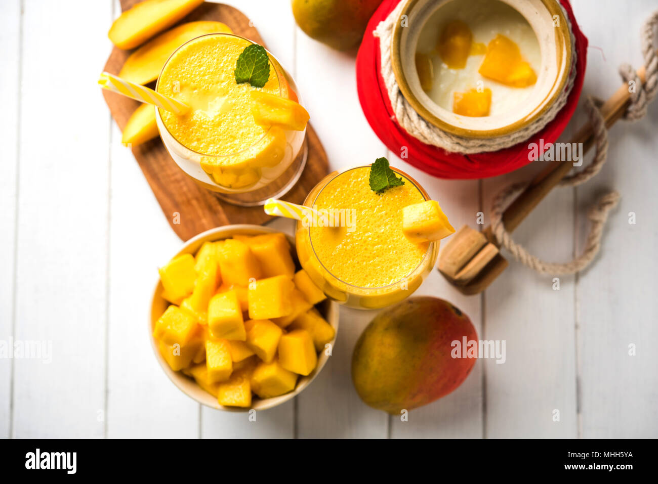 Mango Lassi or smoothie in big glass or small bottles with curd, cut ...