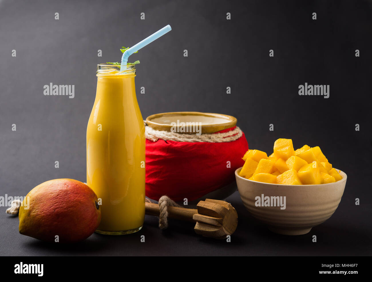 Mango Lassi or smoothie in big glass or small bottles with curd, cut ...