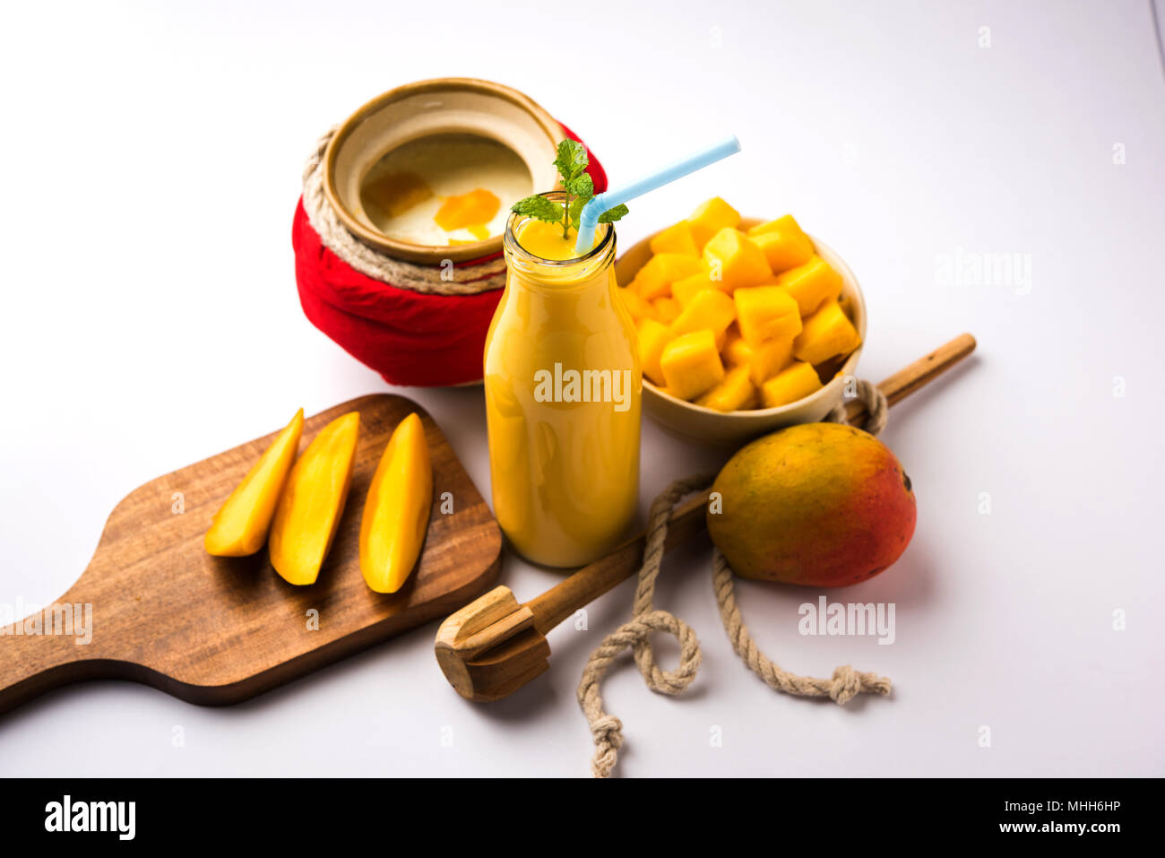 Mango Lassi or smoothie in big glass or small bottles with curd, cut ...