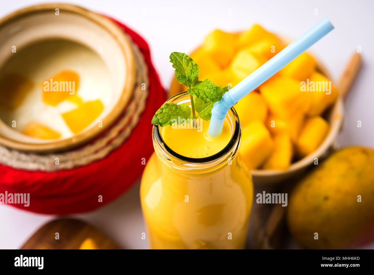 Mango Lassi or smoothie in big glass or small bottles with curd, cut ...