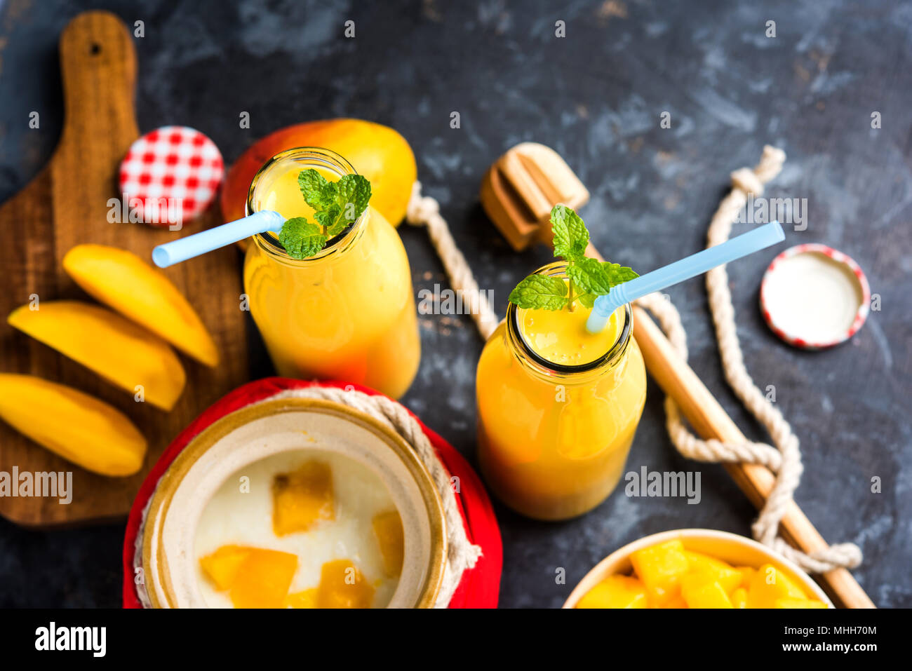 Mango Lassi or smoothie in big glass or small bottles with curd, cut ...