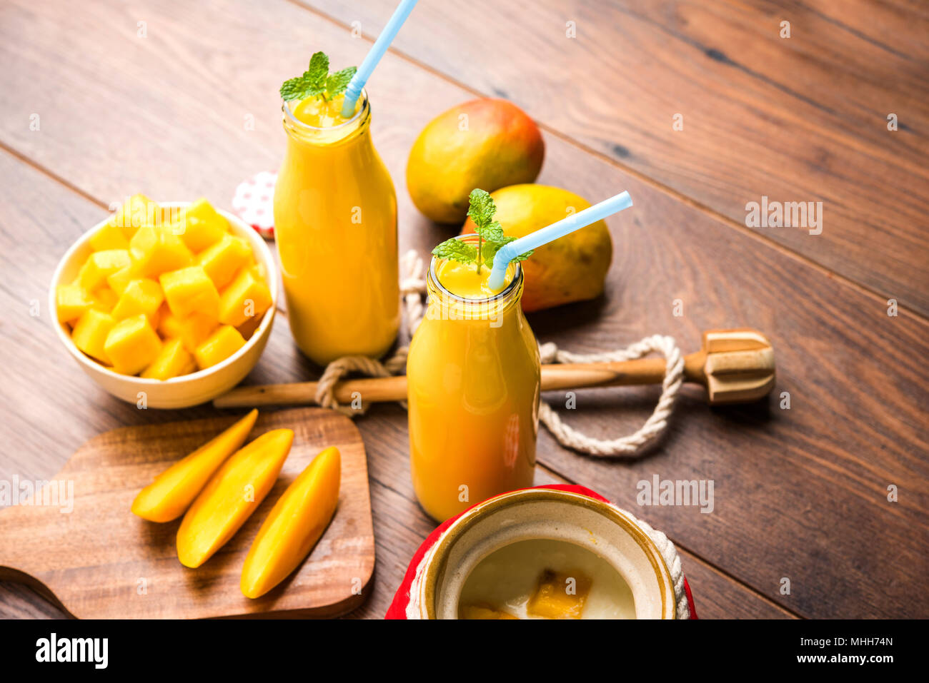 Mango Lassi or smoothie in big glass or small bottles with curd, cut ...