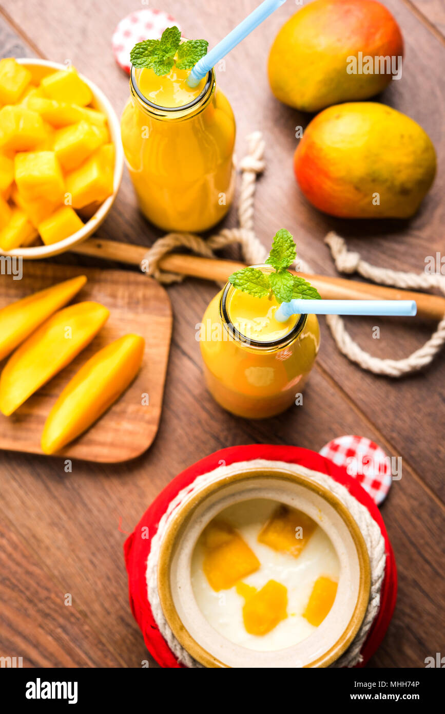 Mango Lassi or smoothie in big glass or small bottles with curd, cut ...