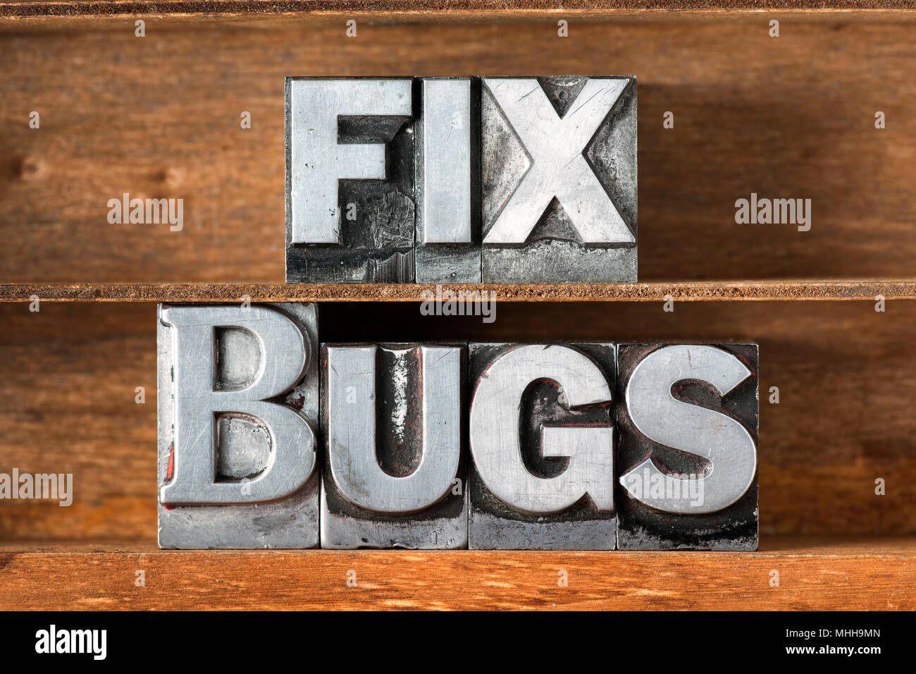 fix bugs phrase made from metallic letterpress type on wooden tray ...