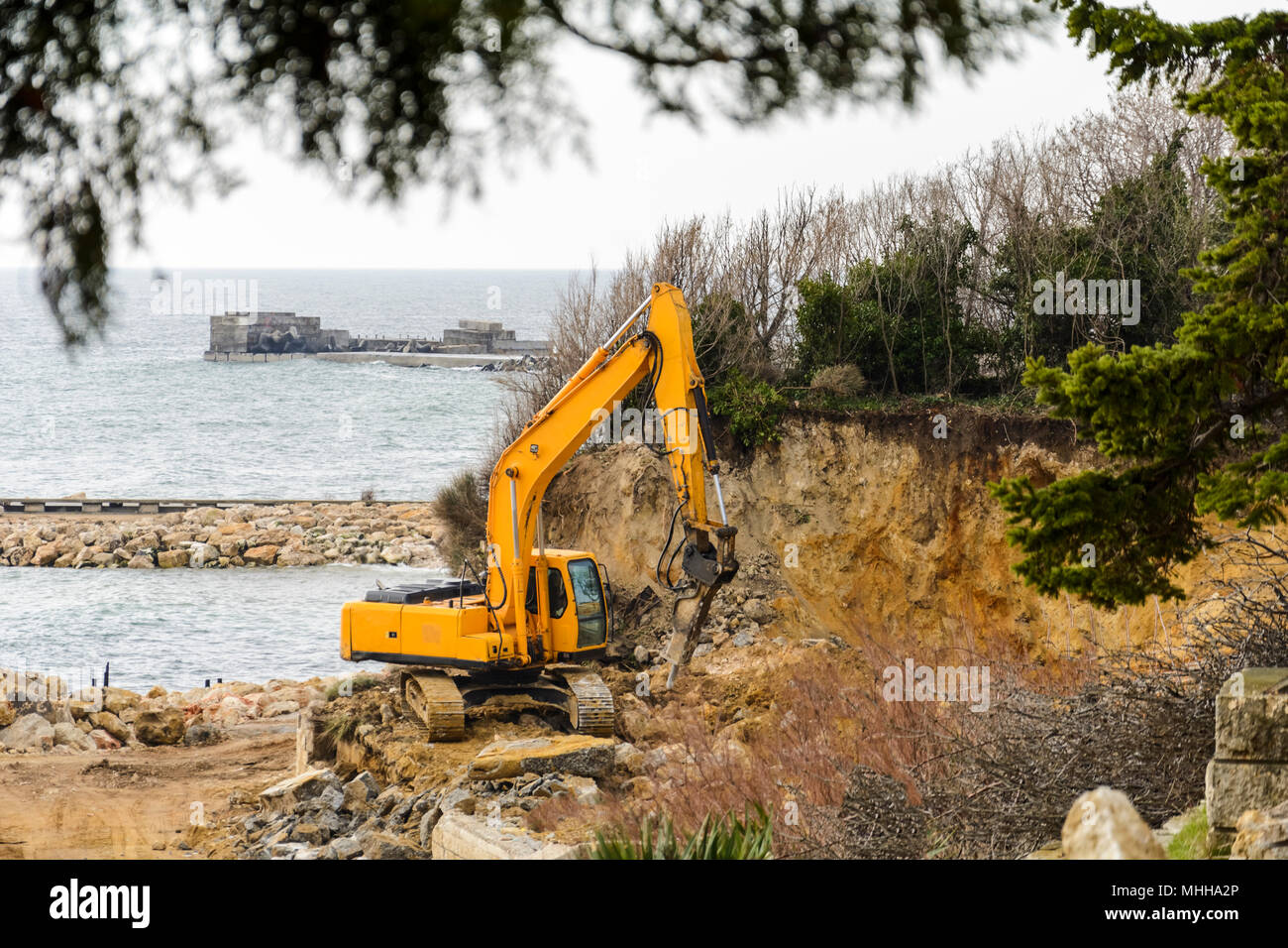 Excavator destroying a beach and a cliff for a hotel construction Stock ...