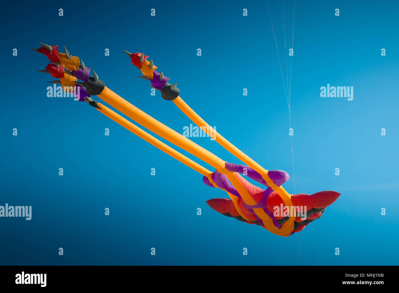 colorful orange kite in the blue sky at Cervia international kite ...