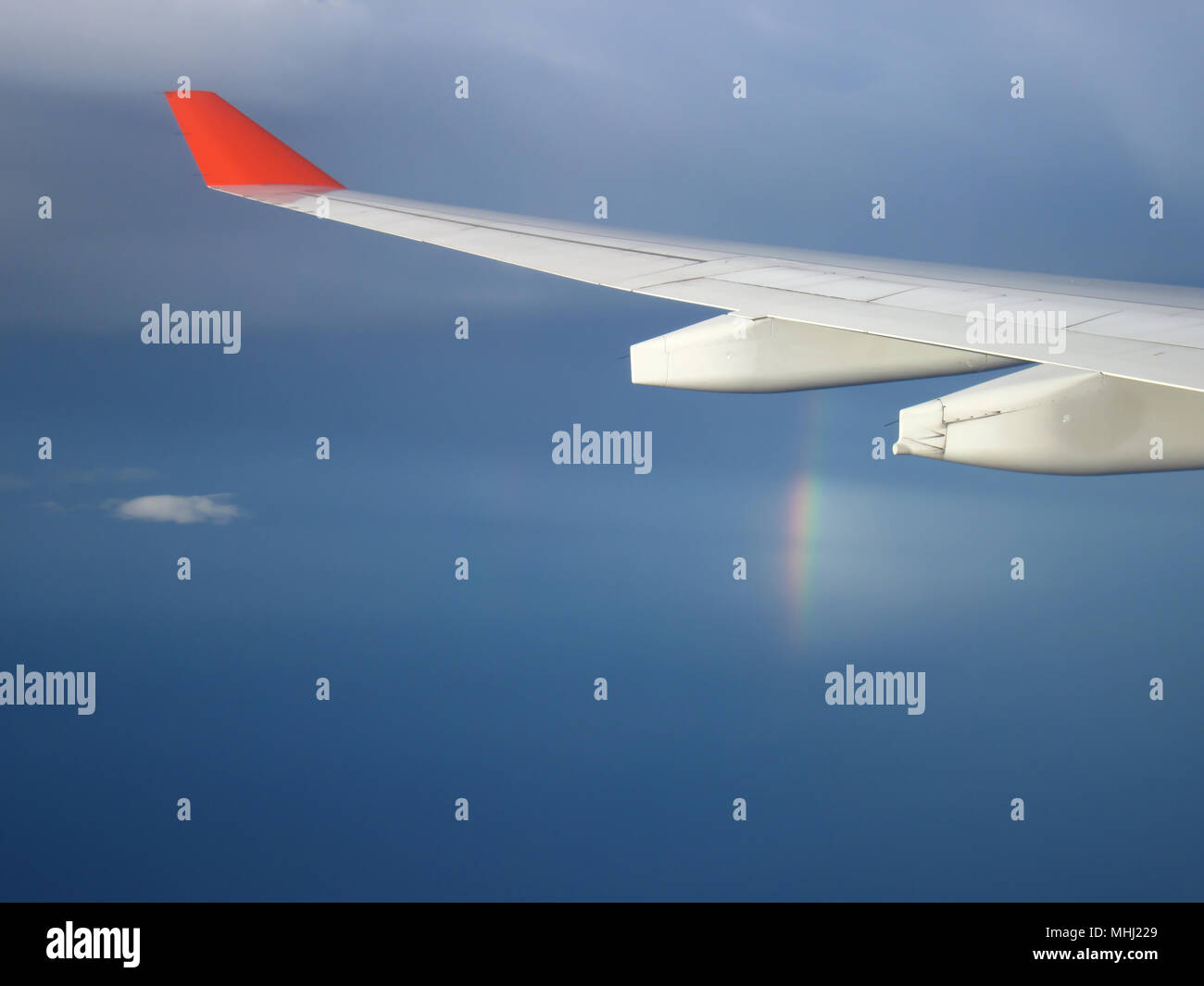 wing of the plane in flight on blue sky with rainbow Stock Photo - Alamy