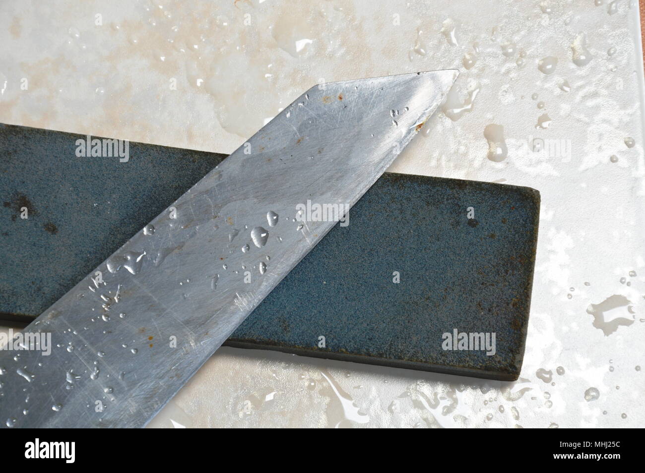 kitchen knife and grindstone on tile floor Stock Photo - Alamy
