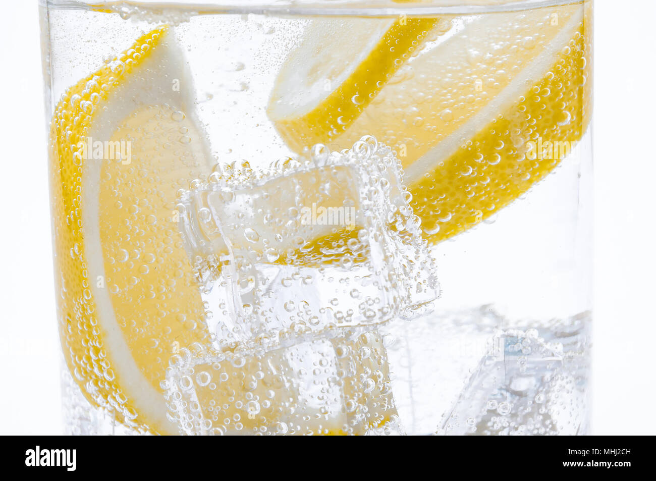 Slices of fresh juicy lemon drop into the cocktail with crystal clear ...
