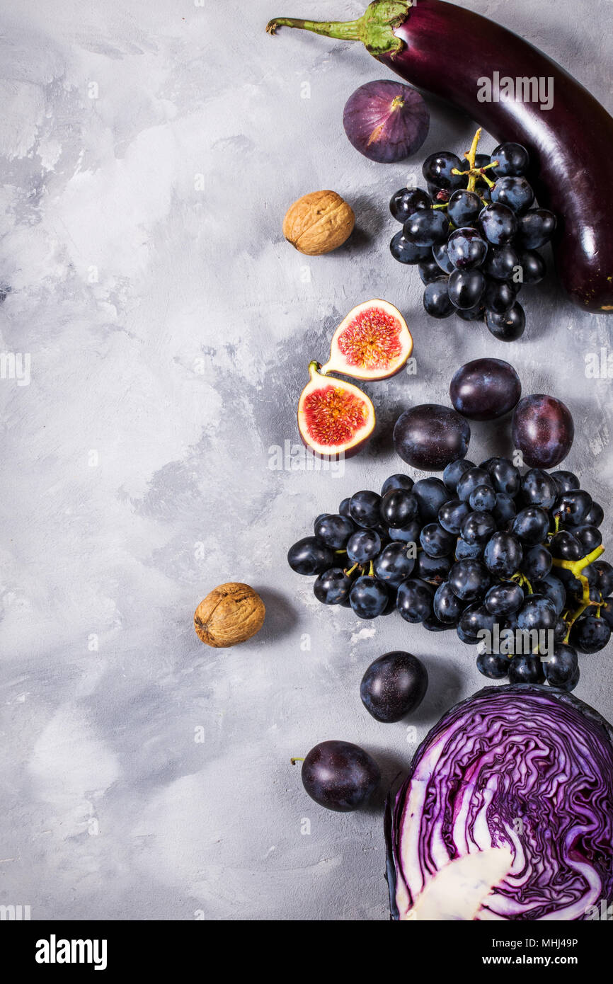 Fresh organic raw purple colored vegetables and fruits on stone ...