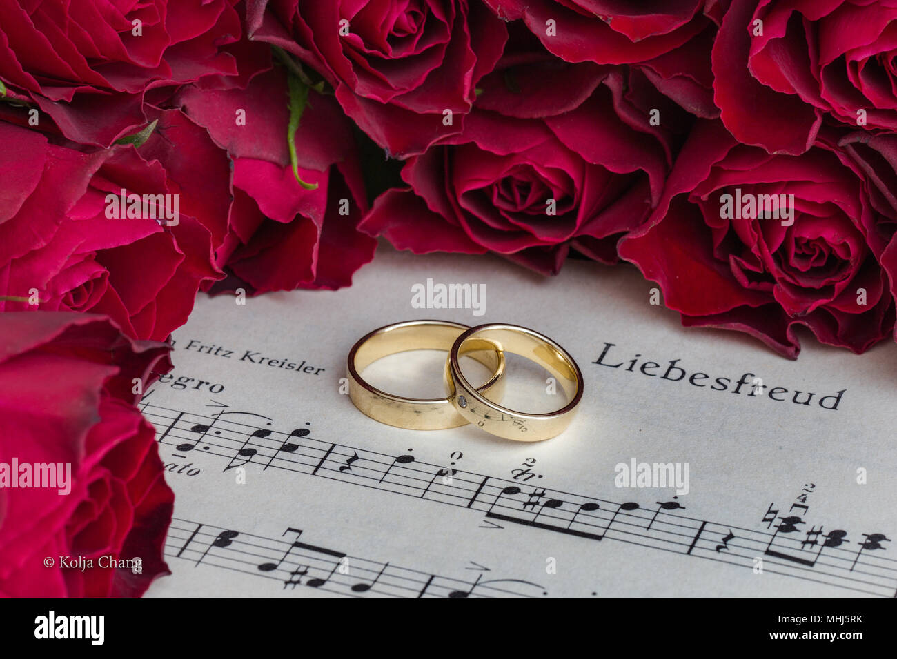 Two Wedding rings surrounded by Roses on a music sheet Stock Photo - Alamy
