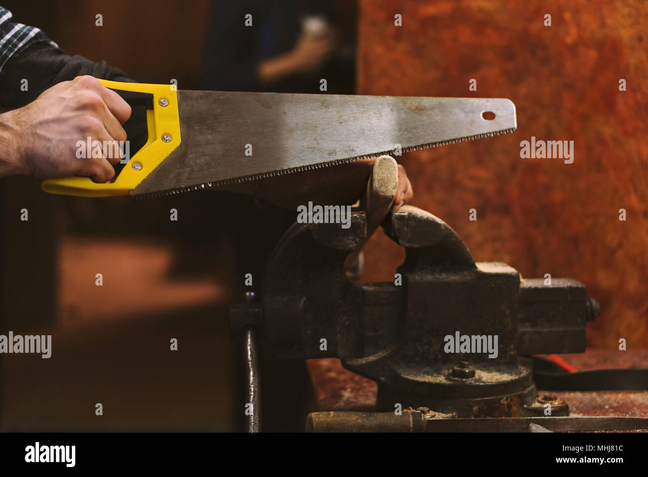 Man working in carpentry workshop. He cuts off excess part of saw from ...