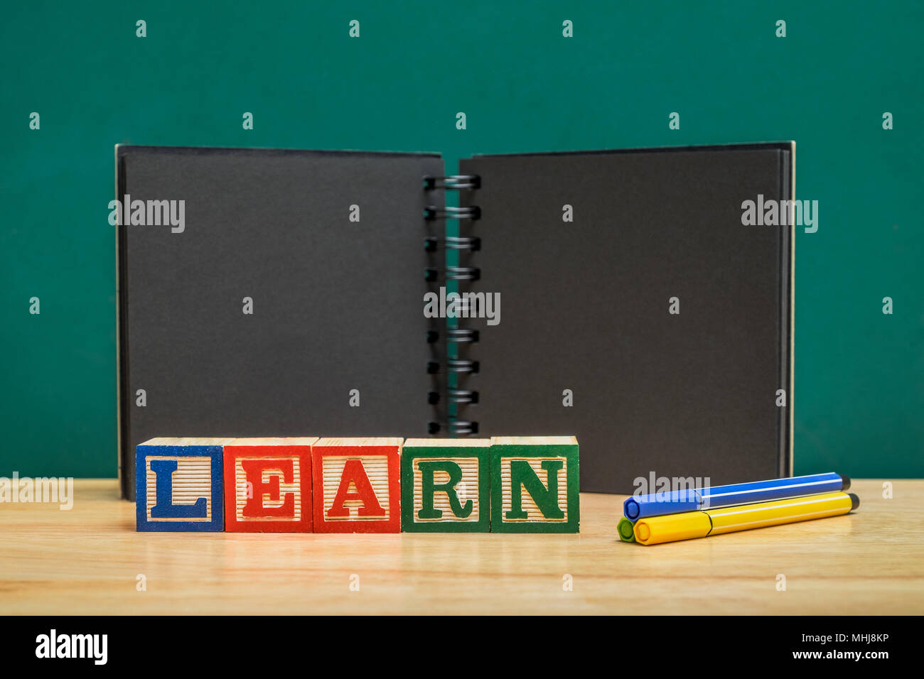 Learn wood block and black notebook on wood table with green blackboard ...