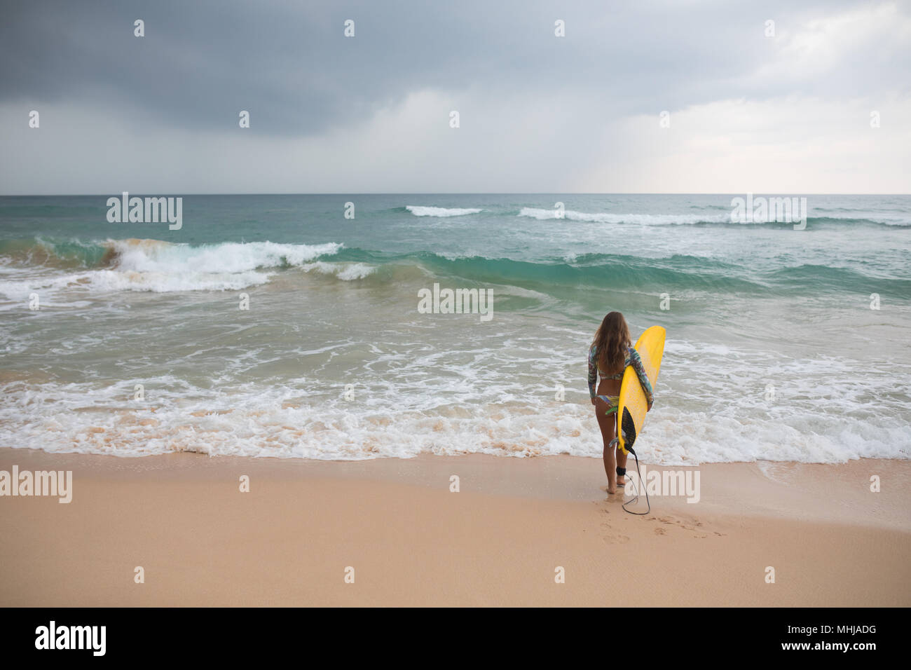Beautiful woman surfer stands on the ocean background with surfboard in ...