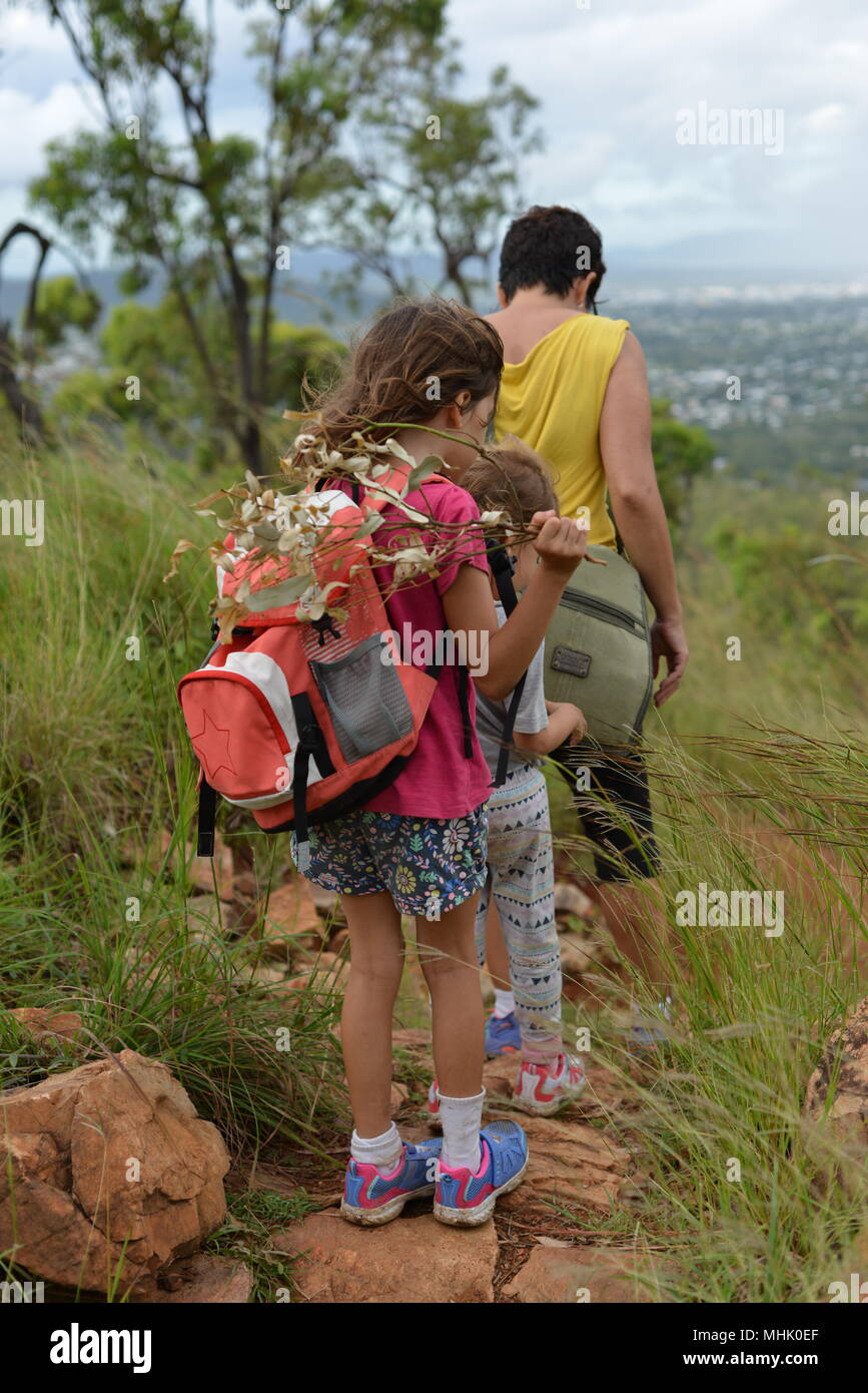 Mother and children walking through long grass through a forest in an ...