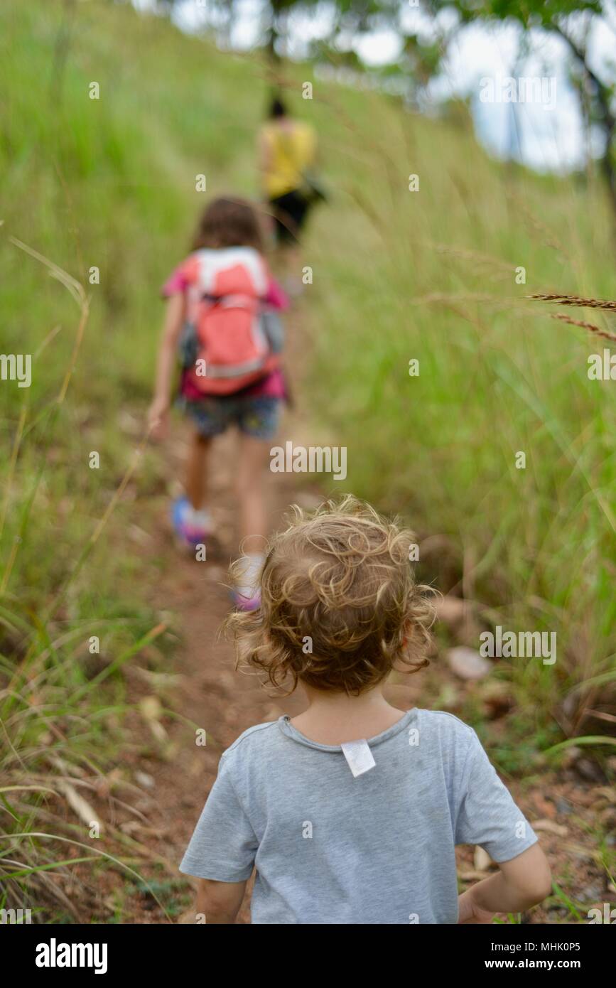 Mother and children walking through long grass through a forest in an ...