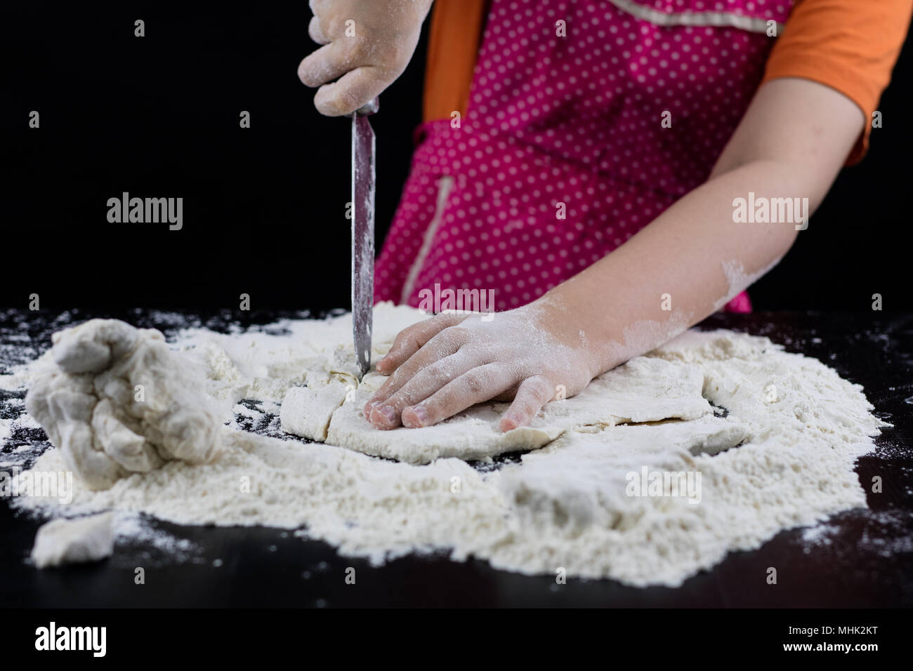 Kneading dough on a black table in a bakery. Baker's hands preparing ...