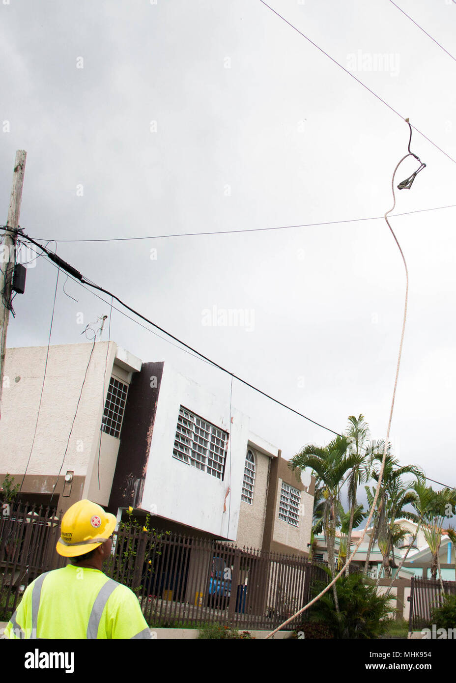 A line worker tosses a guide rope over an existing cable. He will use ...