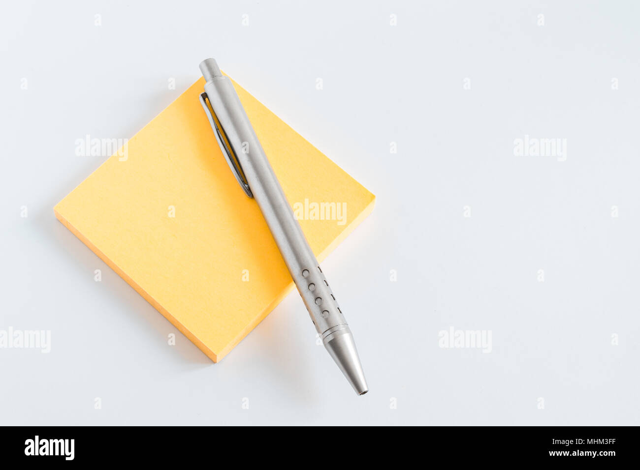 Yellow sticky notes with metallic ballpoint pen on a white background ...