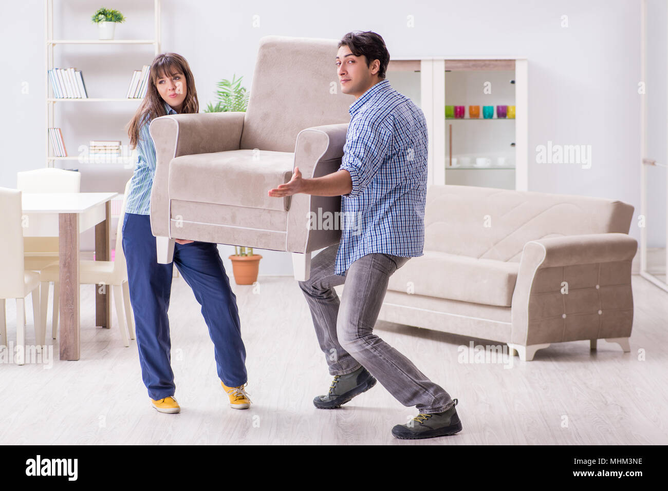 Man moving armchair in the living room Stock Photo - Alamy