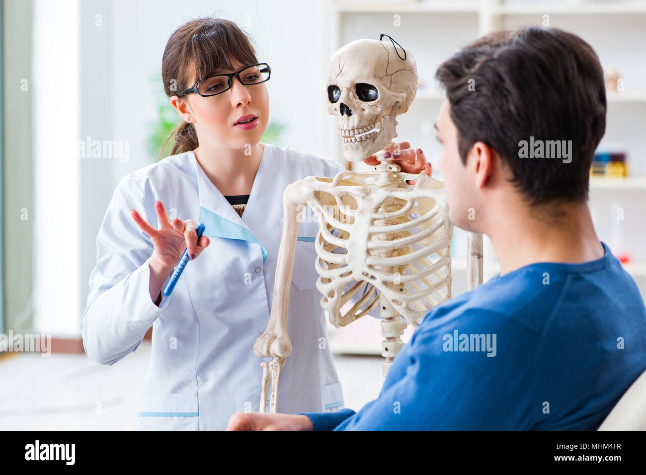 Doctor showing type of injury on skeleton to patient Stock Photo - Alamy