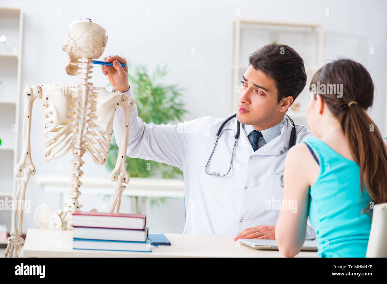Doctor showing type of injury on skeleton to patient Stock Photo - Alamy