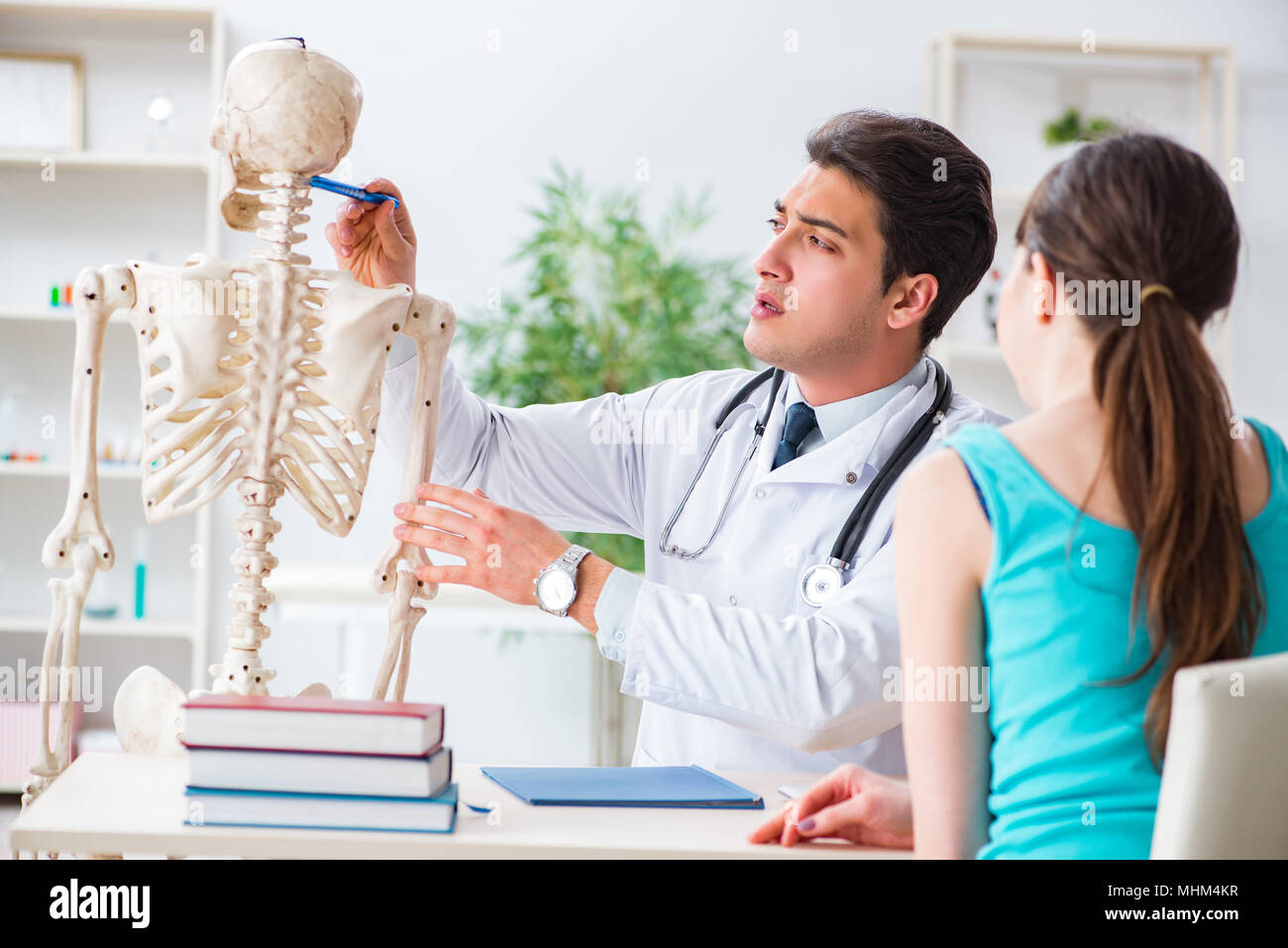 Doctor showing type of injury on skeleton to patient Stock Photo - Alamy