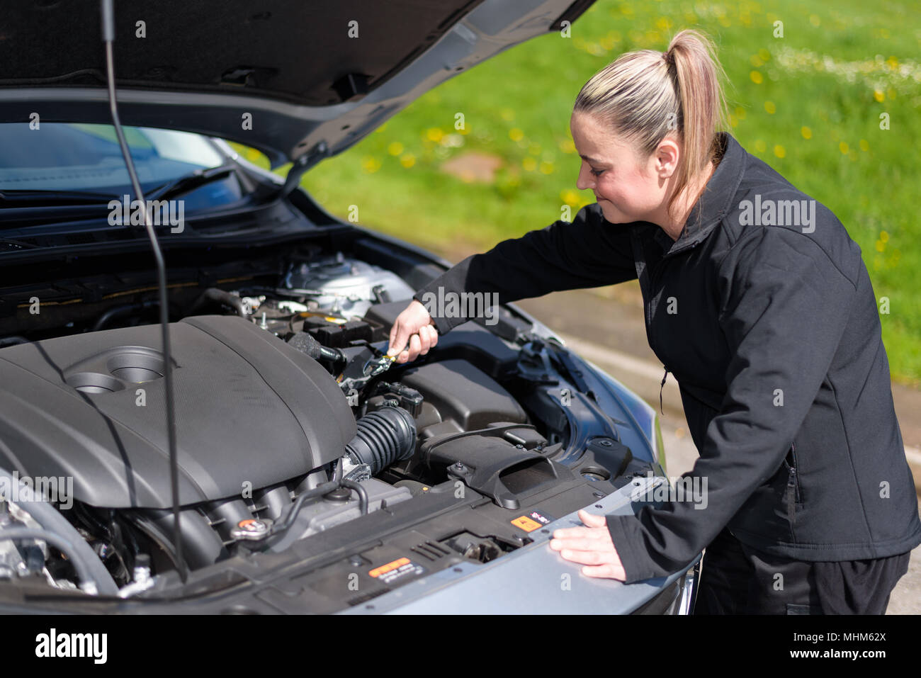 A woman mechanic repairing a car engine at roadside Stock Photo - Alamy