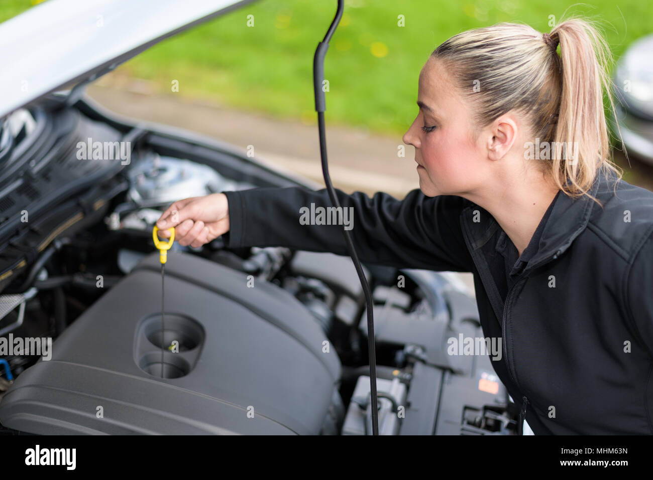 A woman mechanic checking a car's oil level at roadside Stock Photo - Alamy