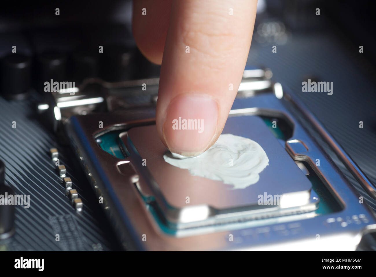 Applying thermal paste with finger in CPU on motherboard close up Stock ...