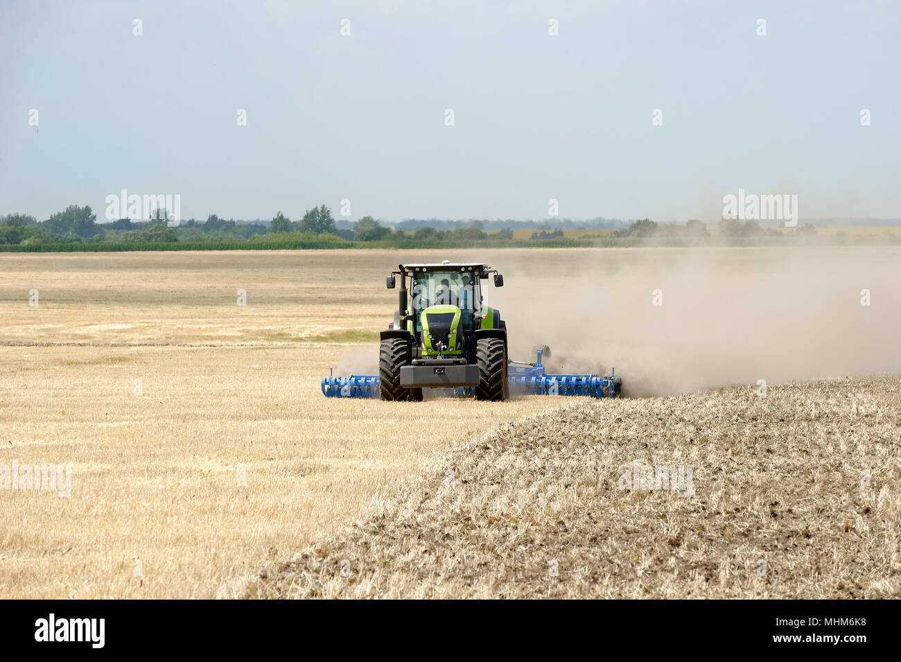 Tractor preparing land with plow, sunny summer day at agricultural ...