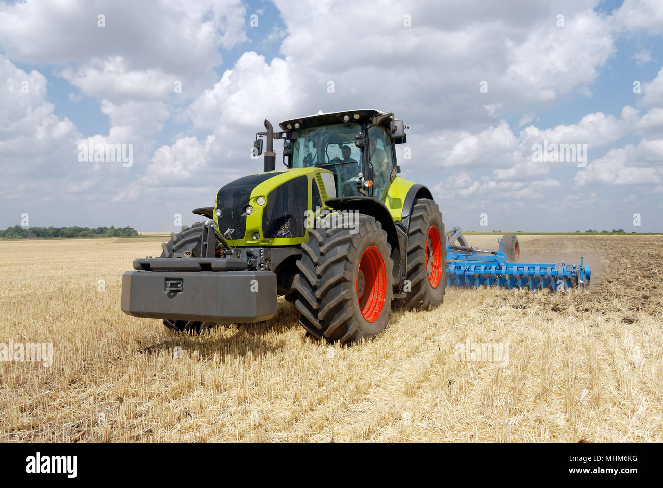 Tractor preparing land with plow, sunny summer day at agricultural ...