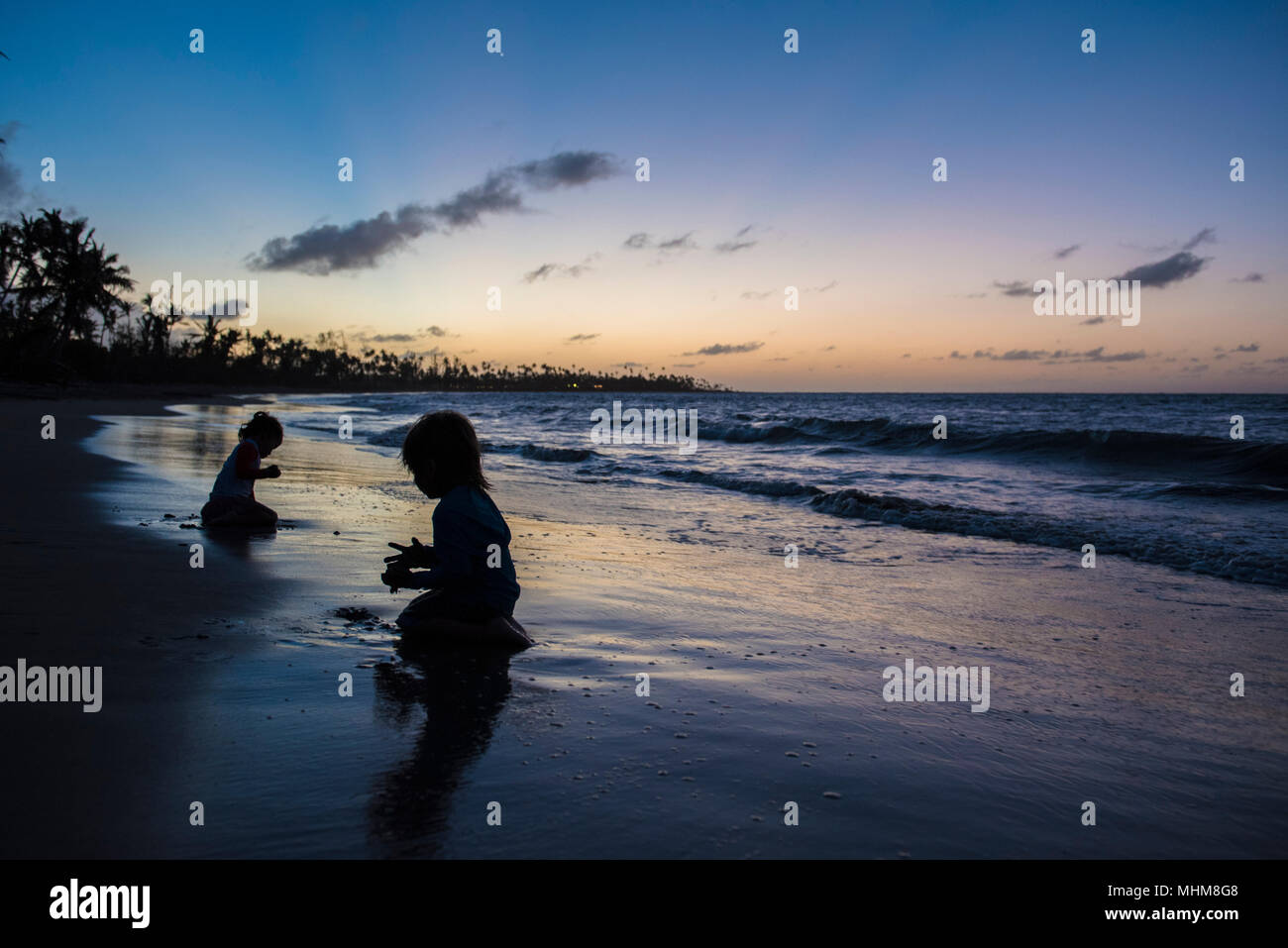 Two kids playing on the beach at sunset Stock Photo - Alamy