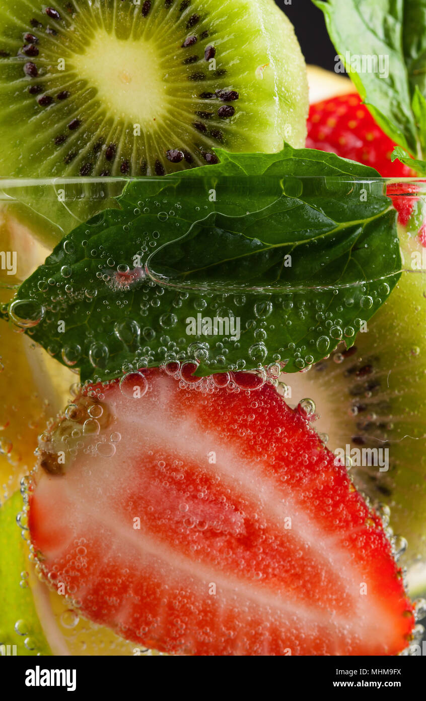 Fresh fruits and berries with mint leaves in a glass of sparkling water ...