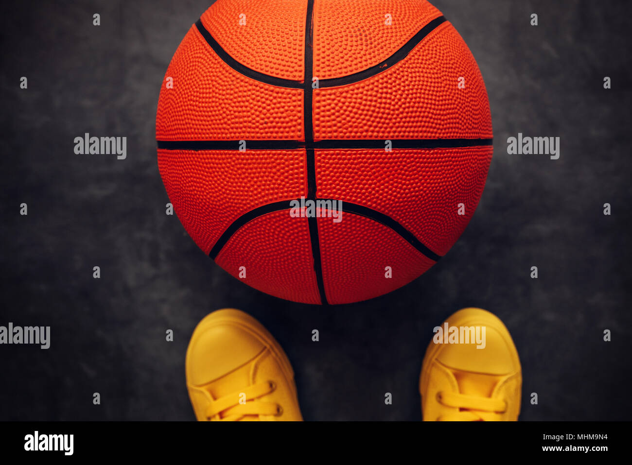 Streetball player standing directly above ball on basketball court with ...