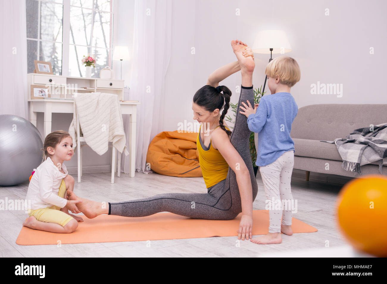 Inspired mother training and kids playing Stock Photo - Alamy