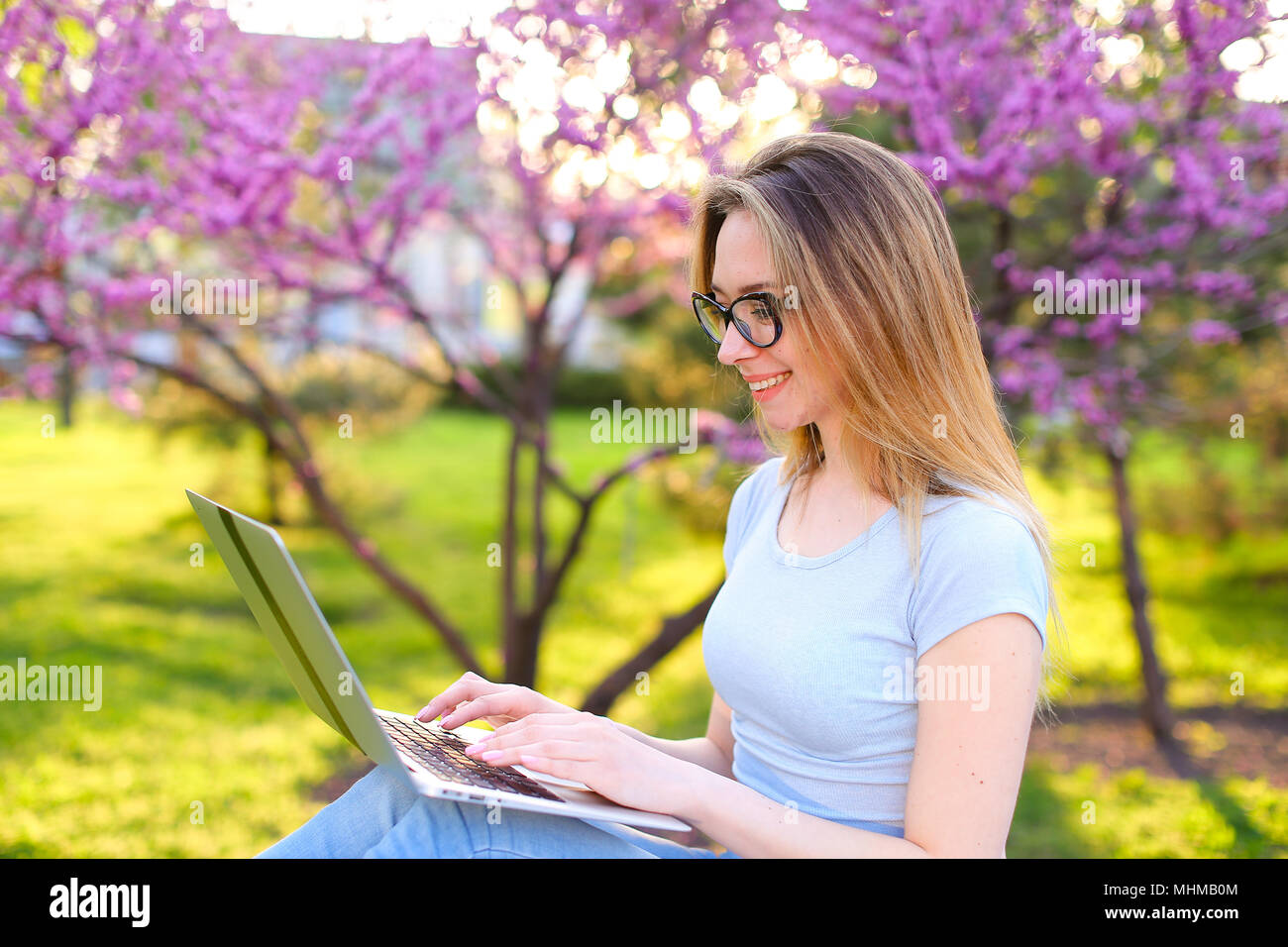 Beautiful girl typing message by laptop with blossom background Stock ...
