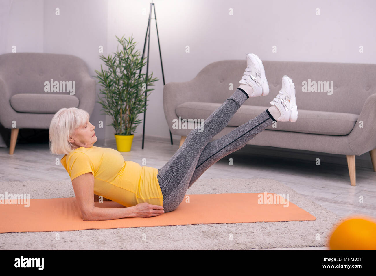 Pleasant senior woman doing leg lift exercise Stock Photo - Alamy