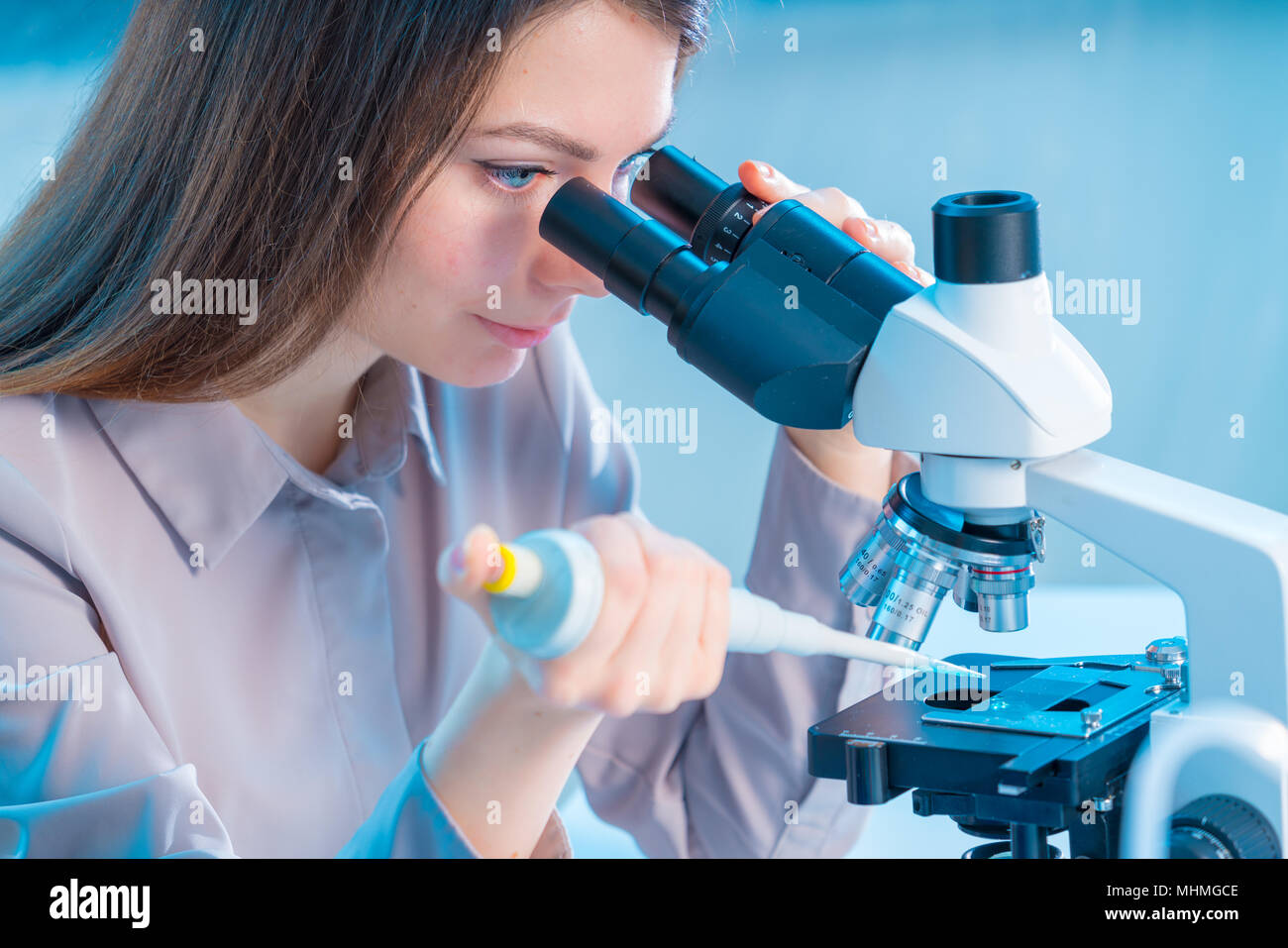 laboratory assistant with a pipette and a microscope in the laboratory ...