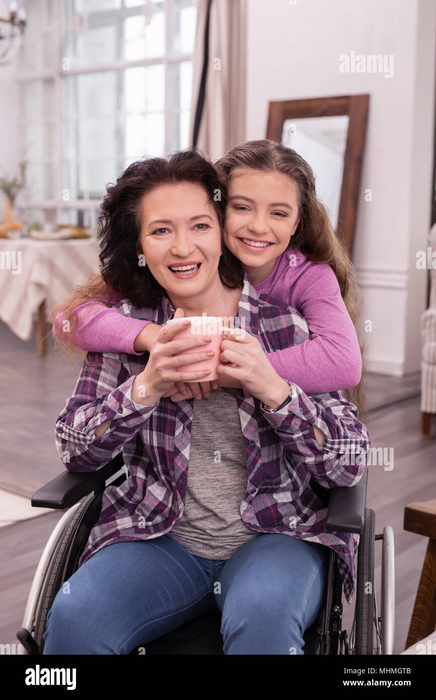 Cheerful girl hugging disabled woman Stock Photo - Alamy