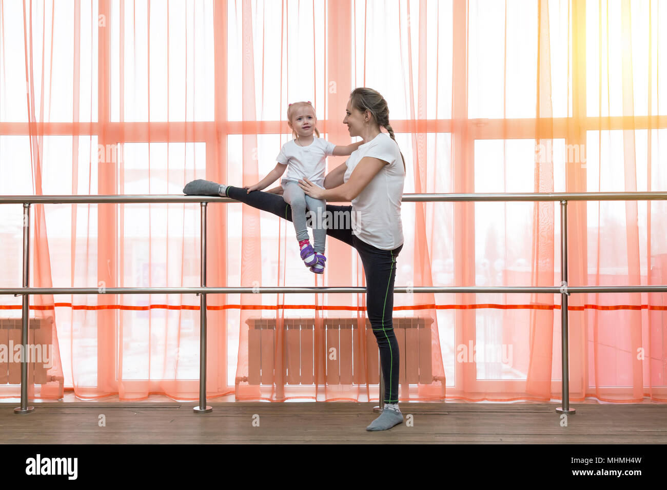 Young woman and little girl doing stretching exercises to get to the ...