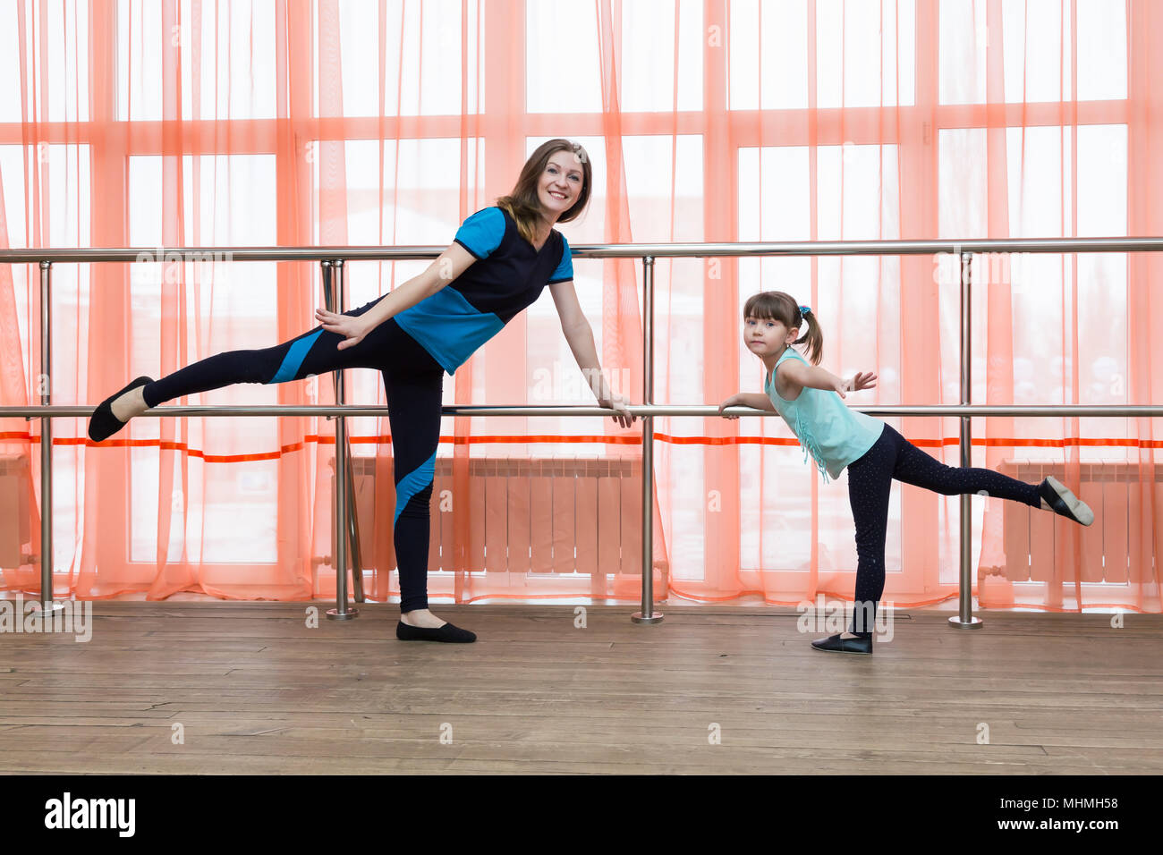 Young woman and little girl doing stretching exercises to get to the ...