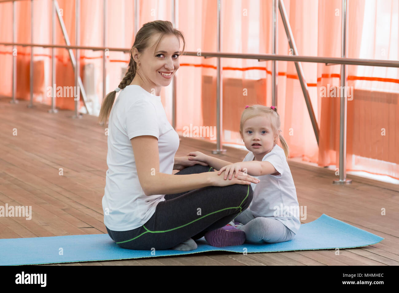 Young woman and little girl are sitting opposite each other on a sports ...