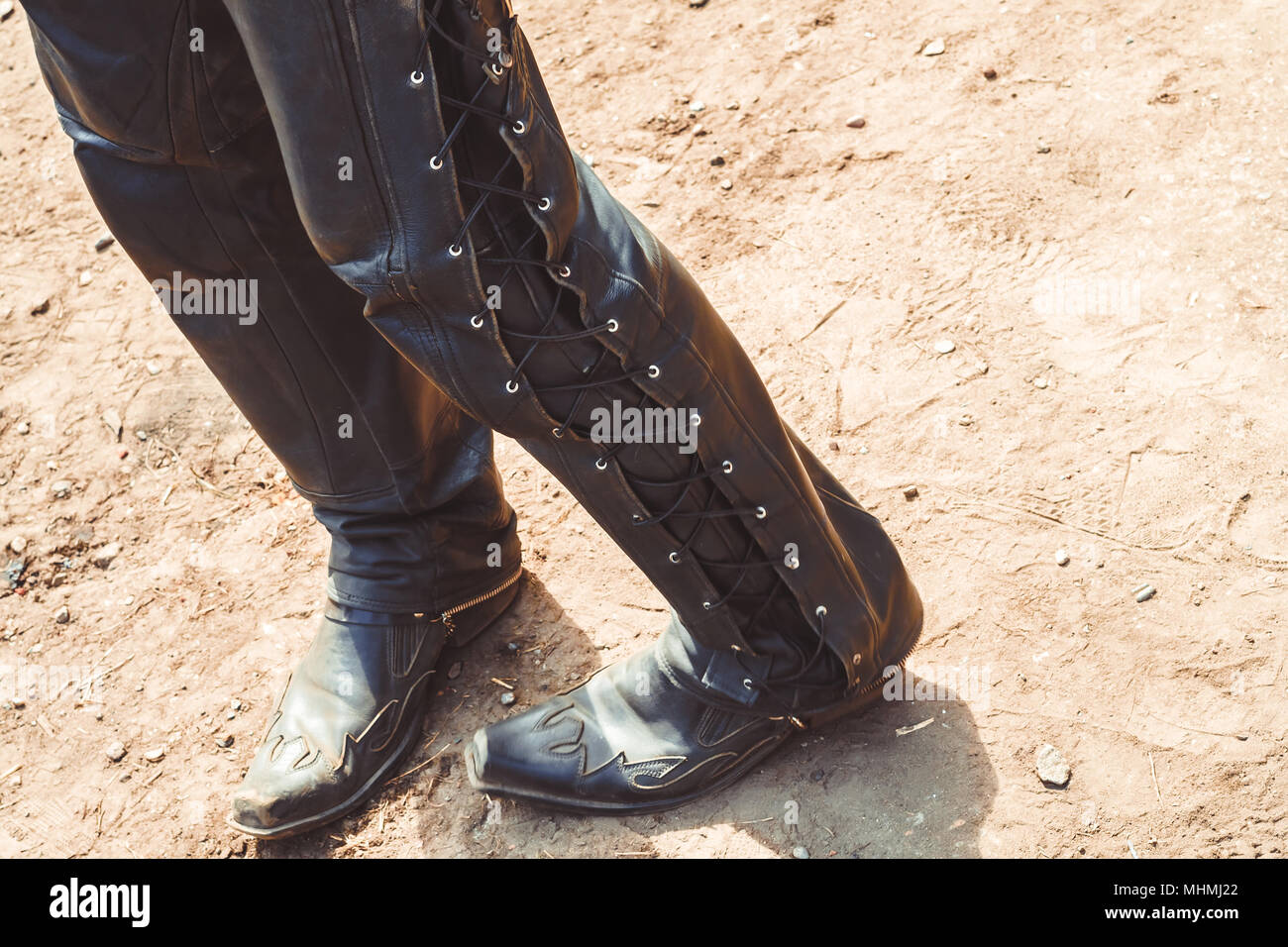 Hard biker in dirty leather pants stands crooked Stock Photo - Alamy
