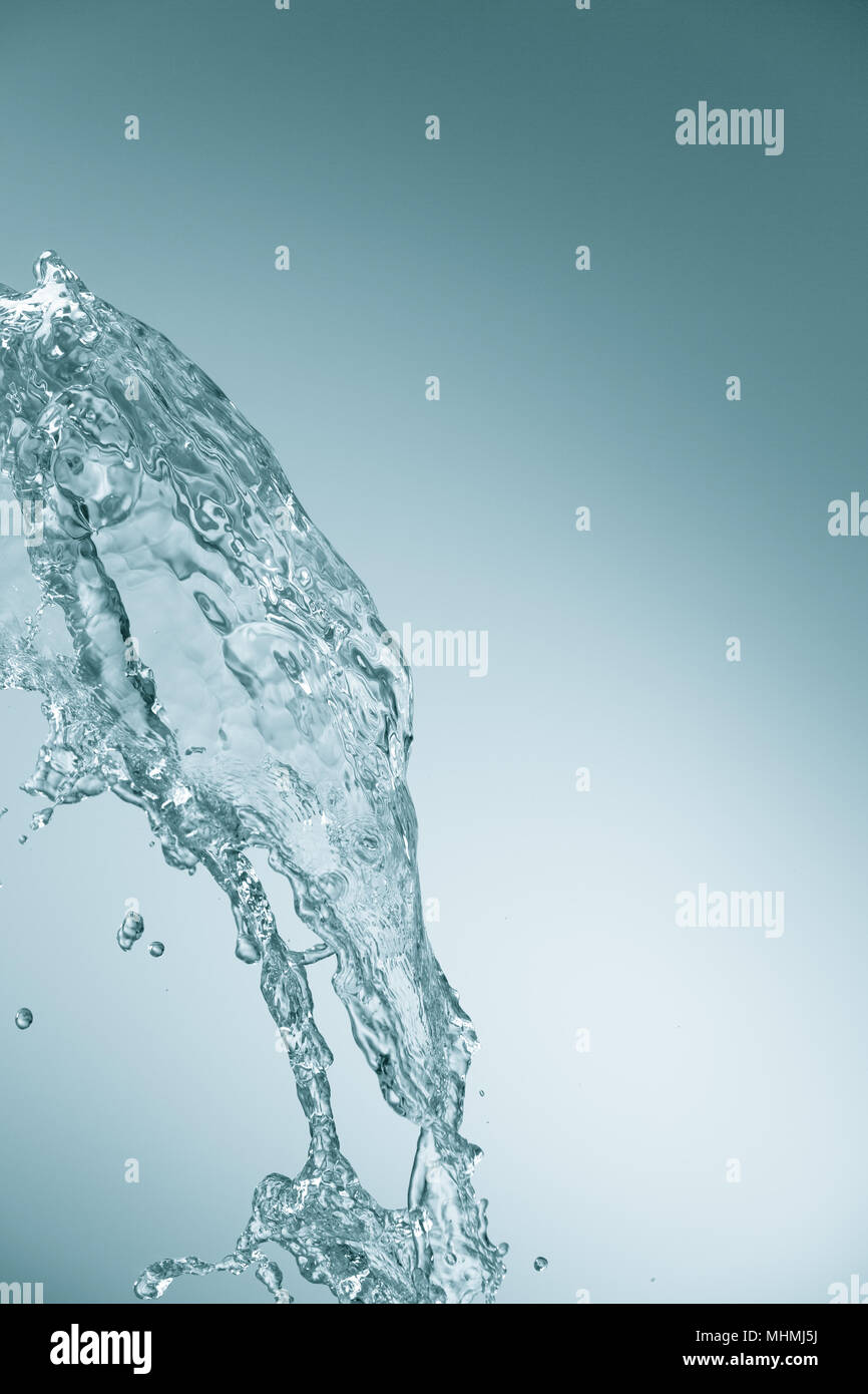 A stream of filtered natural water on a blue background. Splash of ...